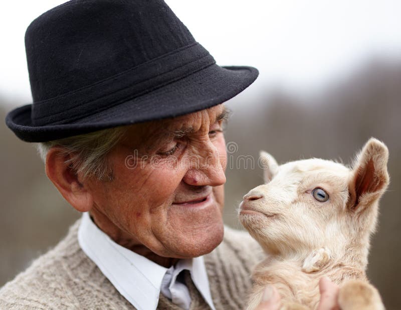 Agricoltore Dell'uomo Che Sorride Tenendo Una Piccola Capra Bianca ...