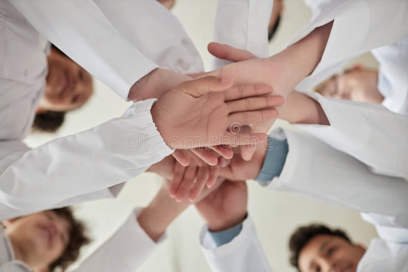 Up View of Children Stacking Hands in Science Class Wearing White Lab ...