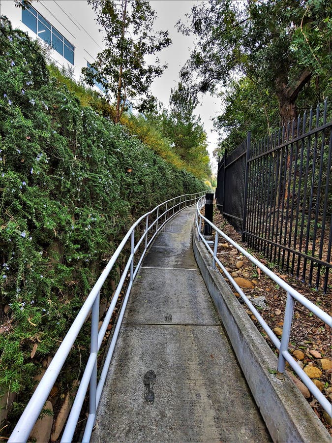 Uphill Concrete Sidewalk Walkway with Metal Railing and Greenery Stock ...