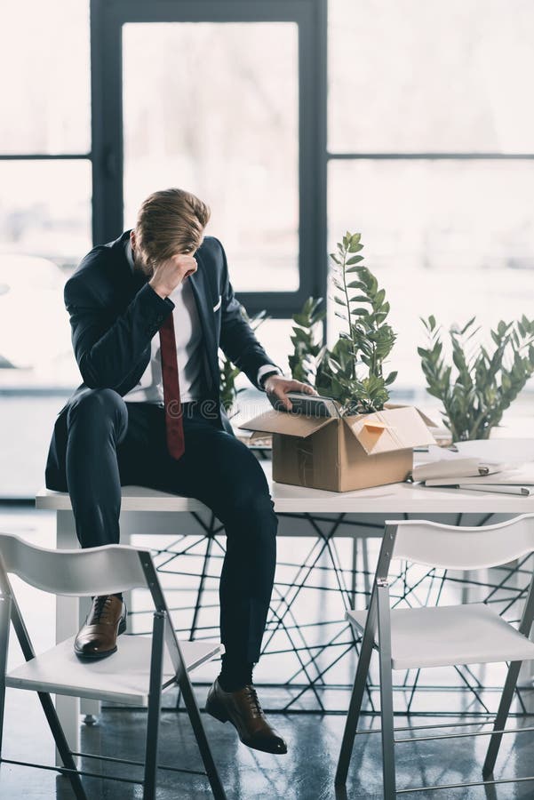 Upset Fired Businessman with Cardboard Box Sitting on Table in Office ...