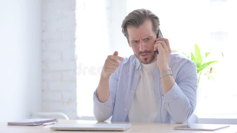Upset Young Man Talking Angrily on Smartphone in Office Stock Photo ...