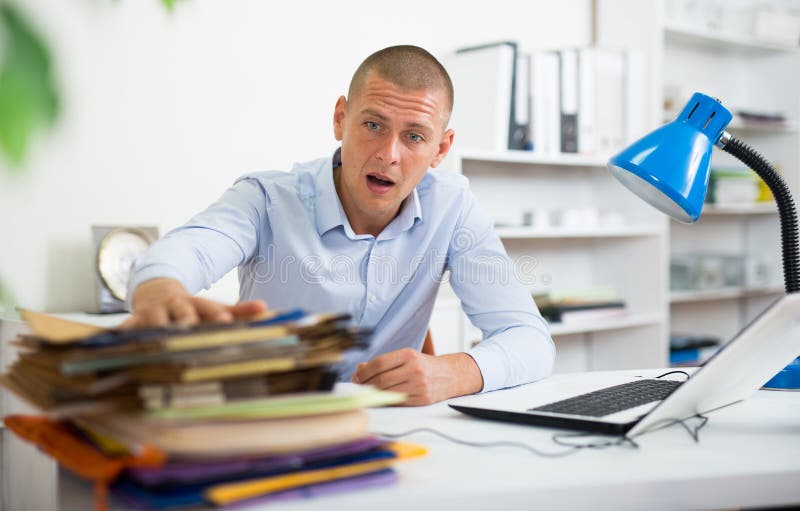 Upset Office Employee Looking at Stack of Documents on Table Stock ...