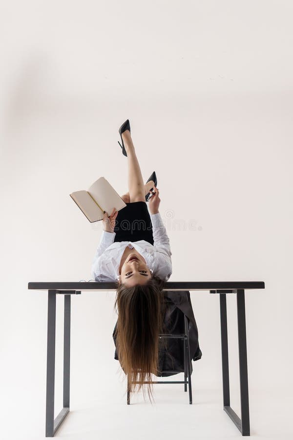Upside-down Businesswoman Reading a Book with Legs on the Table in a ...