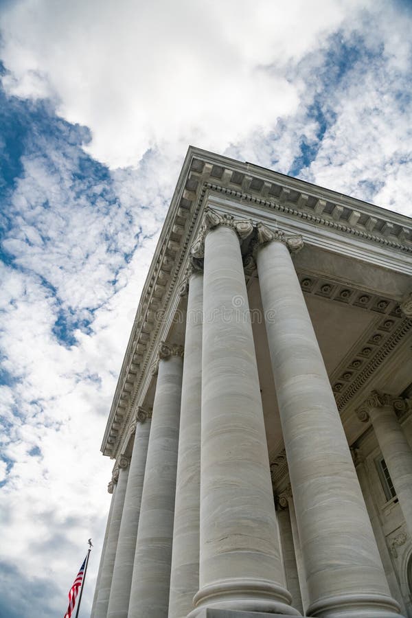 Upward View of Classical Columns Under a Blue Sky with Fluffy Clouds ...