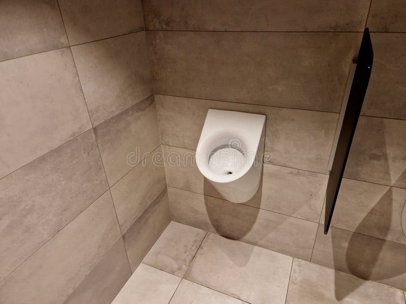 Urinal Lined with Beige Ceramic Tiles. Overhead Lighting from the ...