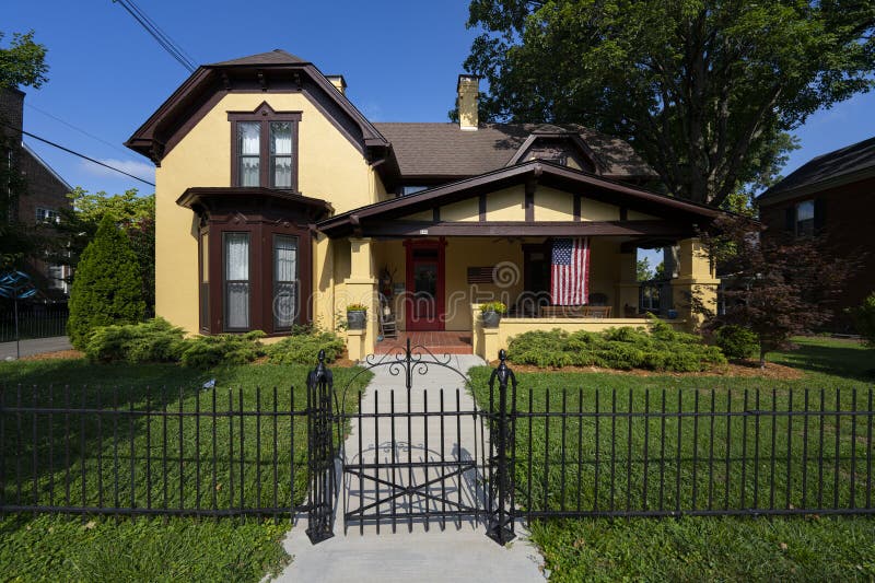 US Flag on Front Porch of Yellow Nicely Painted Home with Front Gate ...