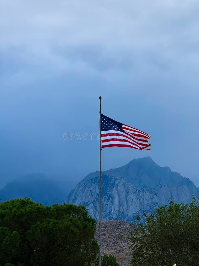 USA American Flag Flying Against Sky and Mountains Stock Photo - Image ...