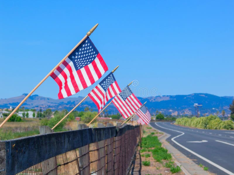 USA Flags Flattering on a Wall Next To a Highway with Mountains in the ...