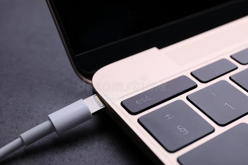 USB Cable with Lightning Connector and Laptop on Black Table, Closeup ...