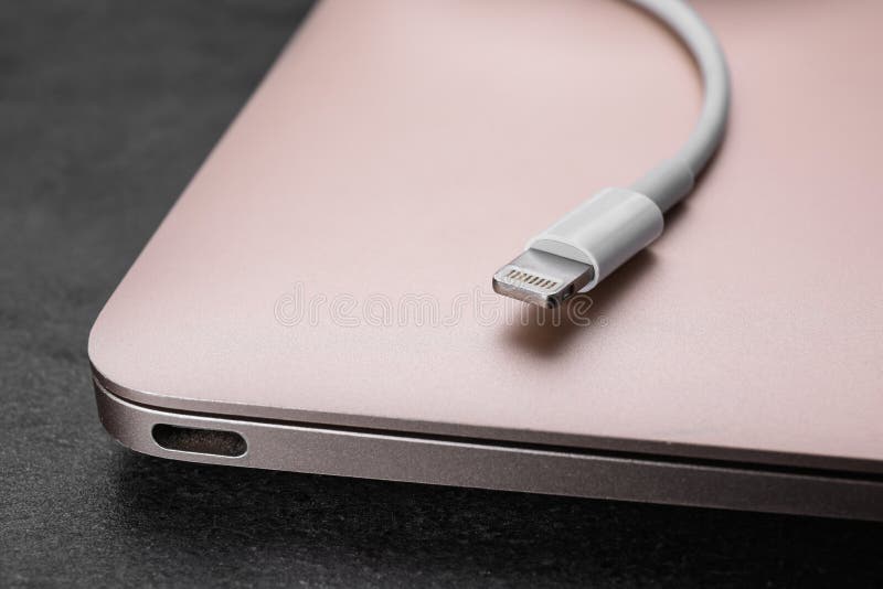 USB Cable with Lightning Connector and Laptop on Black Table, Closeup ...