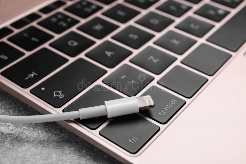 USB Cable with Lightning Connector and Laptop on Grey Table, Closeup ...