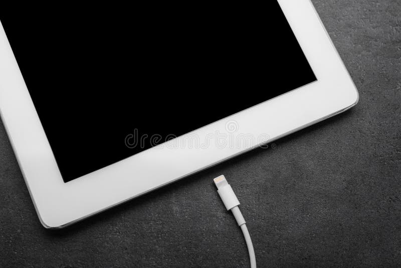 USB Cable with Lightning Connector and Tablet on Dark Table, Closeup ...