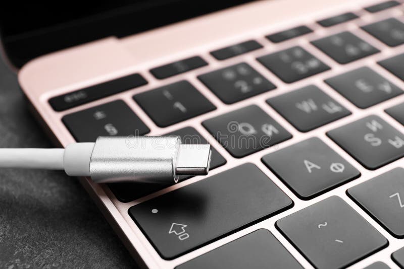 USB Cable with Type C Connector and Laptop on Grey Table, Closeup Stock ...