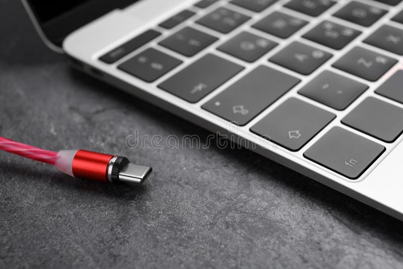 USB Cable with Type C Connector and Laptop on Grey Table, Closeup Stock ...