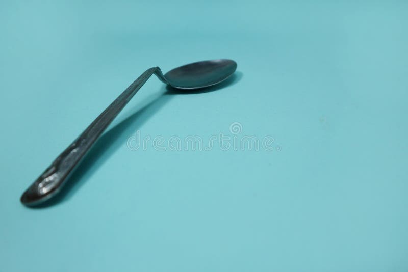 A Used and Bent Spoon, on a Blue Background. Stock Photo - Image of ...