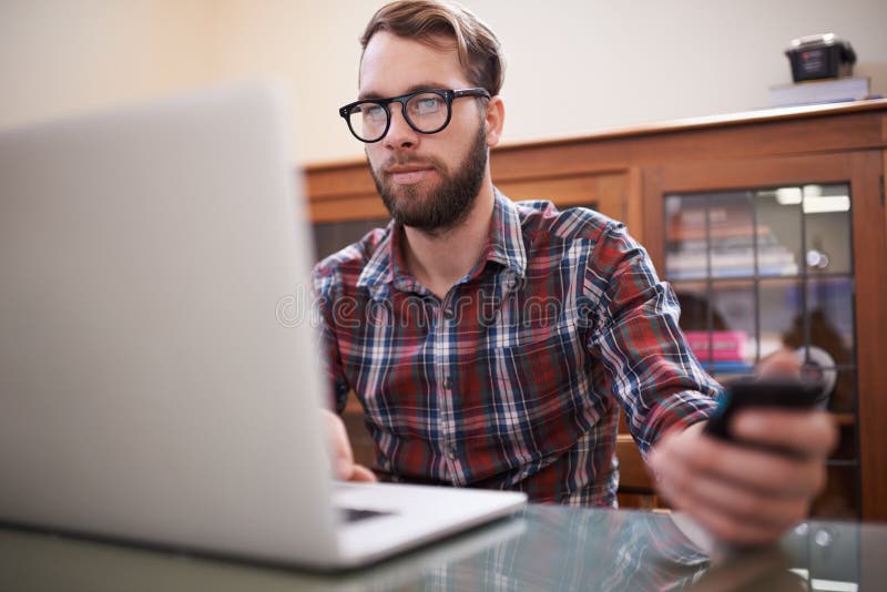 Using All the Latest Tech. a Handsome Young Hipster Working on a Laptop ...