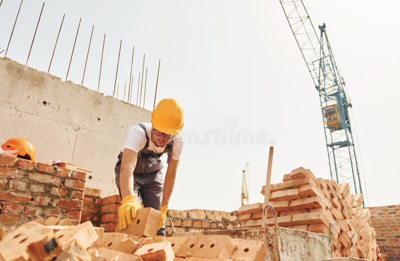Using Bricks. Young Construction Worker in Uniform is Busy at the ...