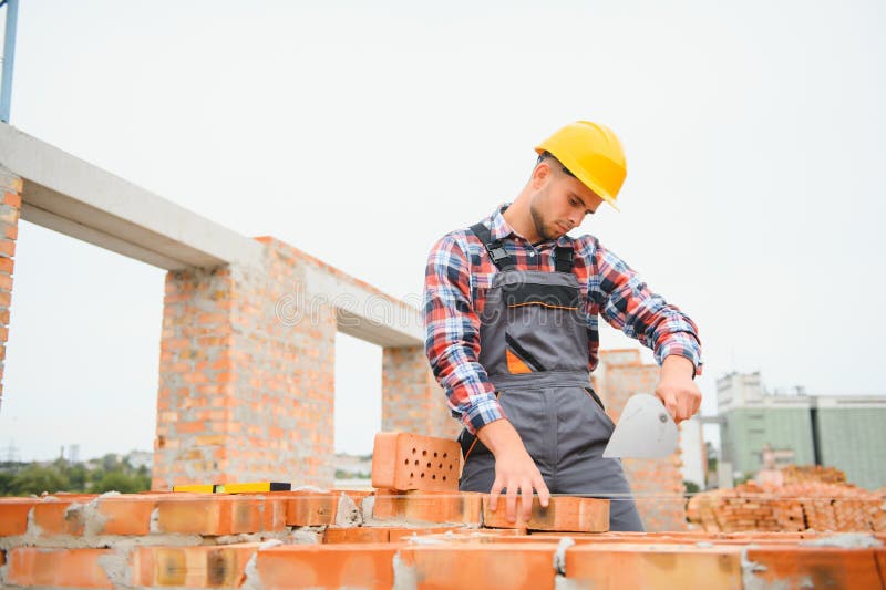 Using Bricks. Young Construction Worker in Uniform is Busy at the ...