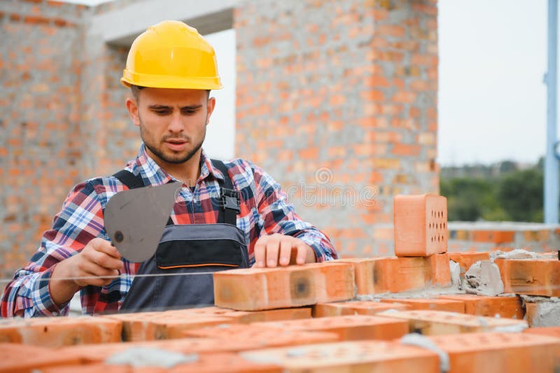 Using Bricks. Young Construction Worker in Uniform is Busy at the ...