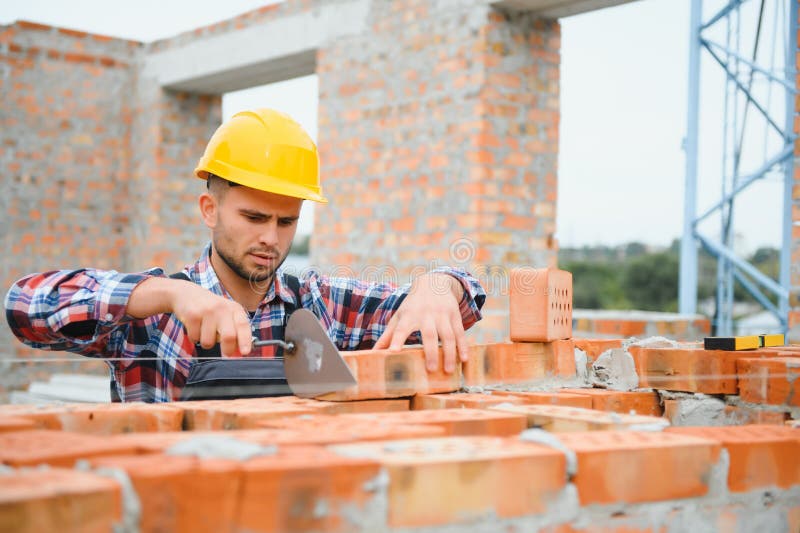 Using Bricks. Young Construction Worker in Uniform is Busy at the ...
