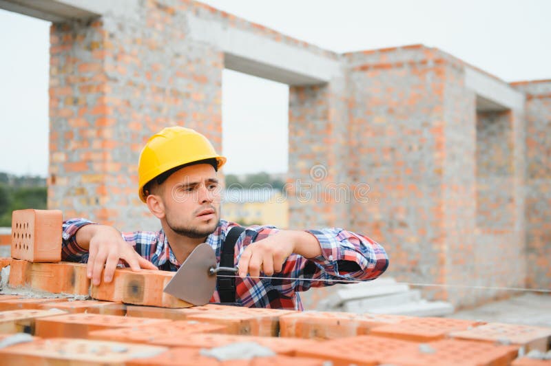 Using Bricks. Young Construction Worker in Uniform is Busy at the ...
