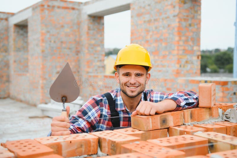 Using Bricks. Young Construction Worker in Uniform is Busy at the ...