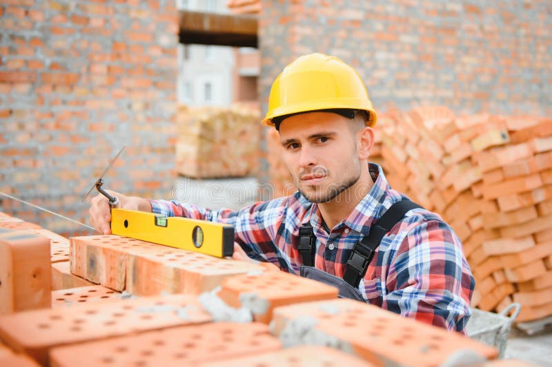 Using Bricks. Young Construction Worker in Uniform is Busy at the ...