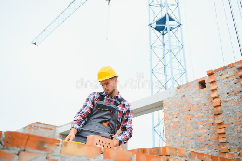 Using Bricks. Young Construction Worker in Uniform is Busy at the ...