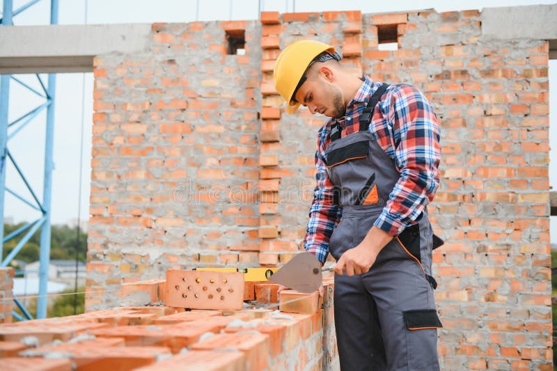 Using Bricks. Young Construction Worker in Uniform is Busy at the ...