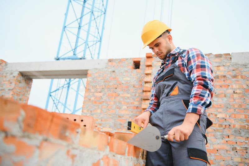 Using Bricks. Young Construction Worker in Uniform is Busy at the ...