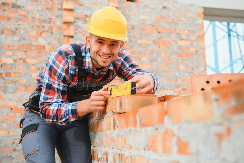 Using Bricks. Young Construction Worker in Uniform is Busy at the ...