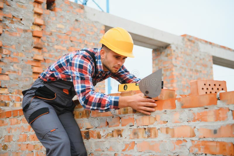 Using Bricks. Young Construction Worker in Uniform is Busy at the ...