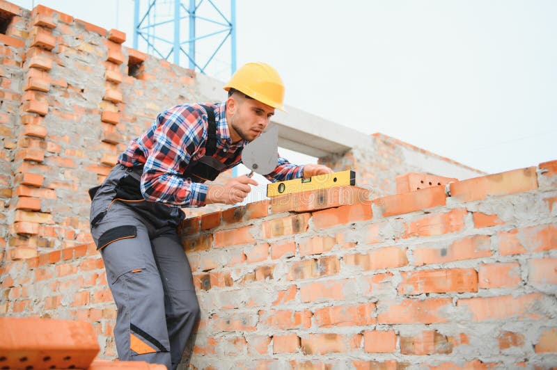 Using Bricks. Young Construction Worker in Uniform is Busy at the ...