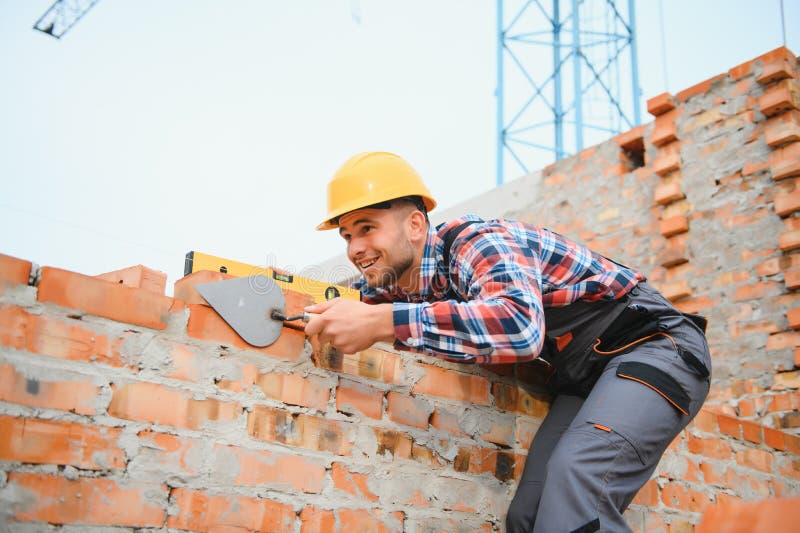 Using Bricks. Young Construction Worker in Uniform is Busy at the ...