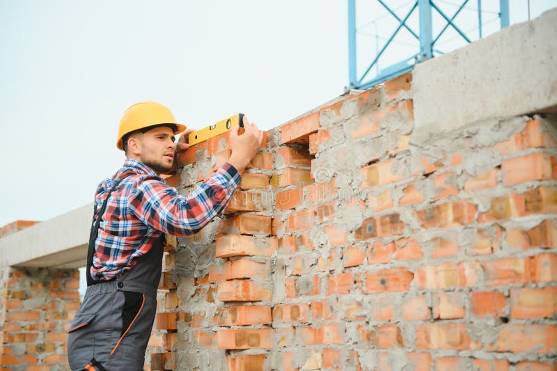 Using Bricks. Young Construction Worker in Uniform is Busy at the ...