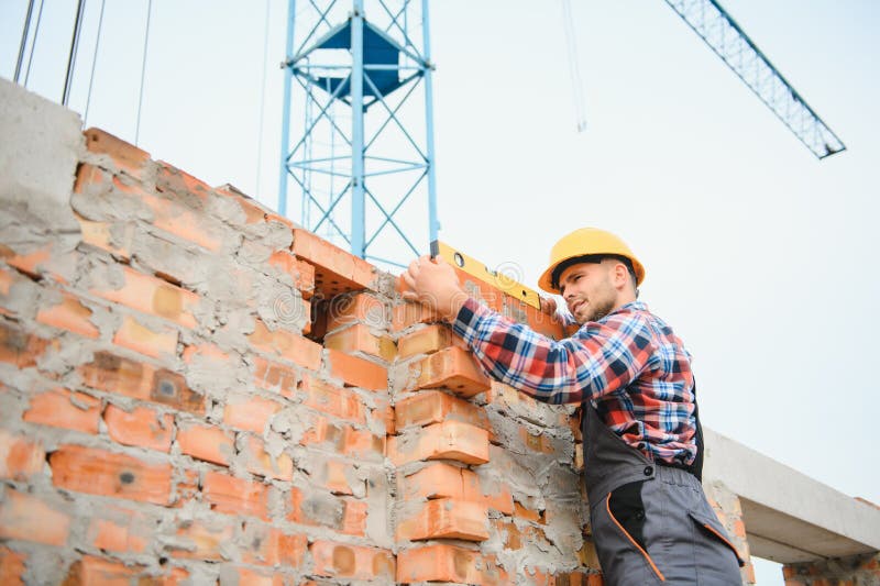 Using Bricks. Young Construction Worker in Uniform is Busy at the ...