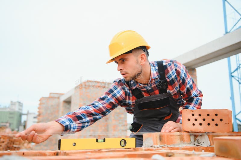Using Bricks. Young Construction Worker in Uniform is Busy at the ...