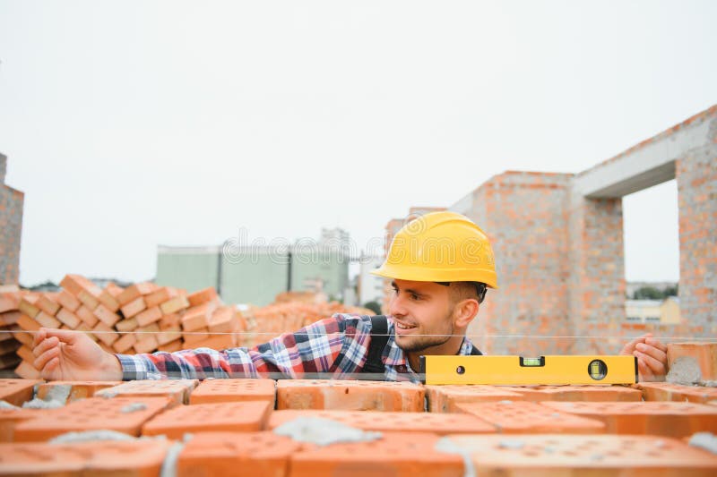 Using Bricks. Young Construction Worker in Uniform is Busy at the ...