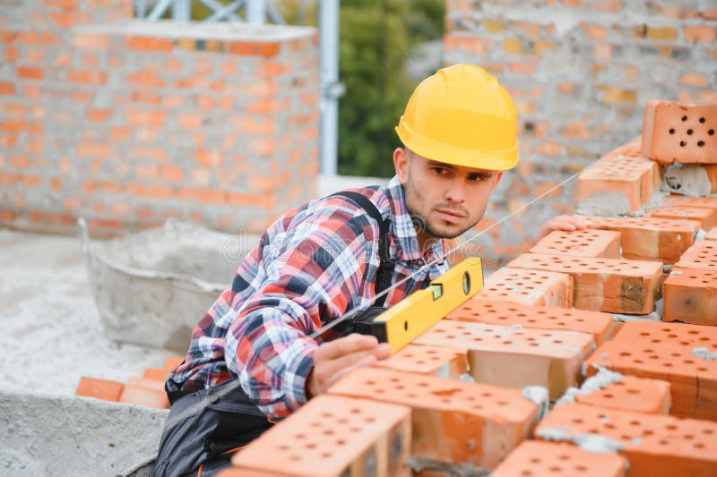Using Bricks. Young Construction Worker in Uniform is Busy at the ...