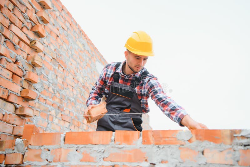 Using Bricks. Young Construction Worker in Uniform is Busy at the ...