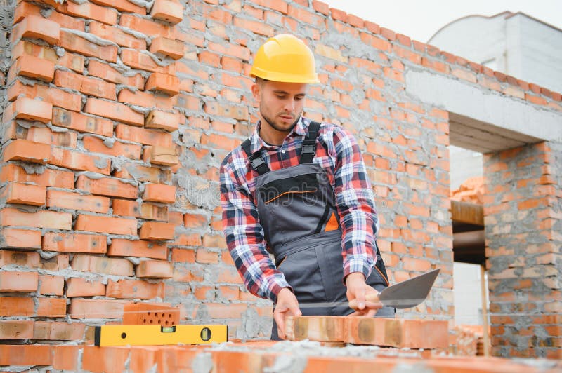 Using Bricks. Young Construction Worker in Uniform is Busy at the ...