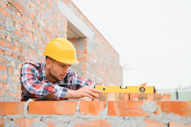 Using Bricks. Young Construction Worker in Uniform is Busy at the ...