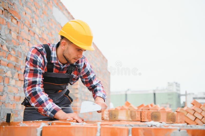 Using Bricks. Young Construction Worker in Uniform is Busy at the ...