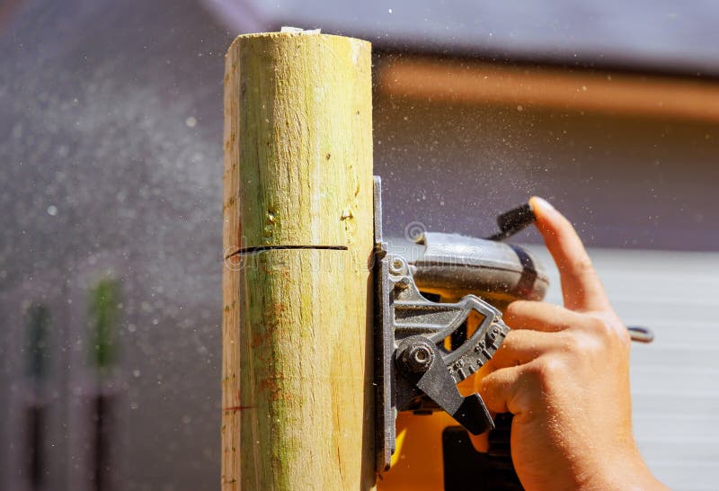 Using an Electric Saw Worker Cuts a Wooden Post for Construction of a ...