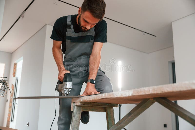 Using Jigsaw To Cut Pieces. Man is Installing New Laminate Wooden Floor ...