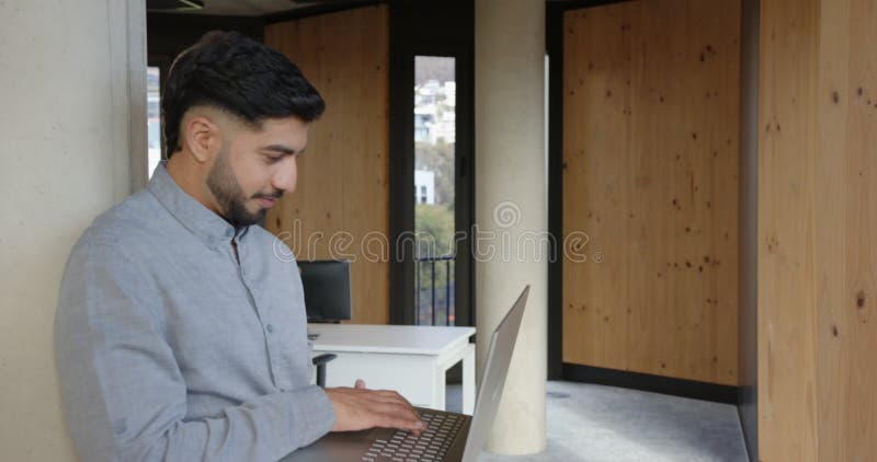 Using Laptop, Indian Man Standing in Modern Office, Concentrating on ...