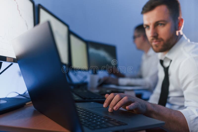Using Laptop. Two Stock Traders Working in the Office with Exchange ...