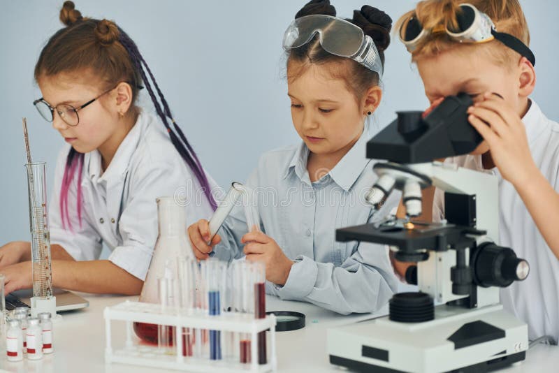 Using Microscope. Children in White Coats Plays a Scientists in Lab by ...
