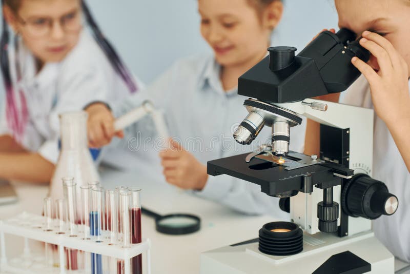 Using Microscope. Children in White Coats Plays a Scientists in Lab by ...