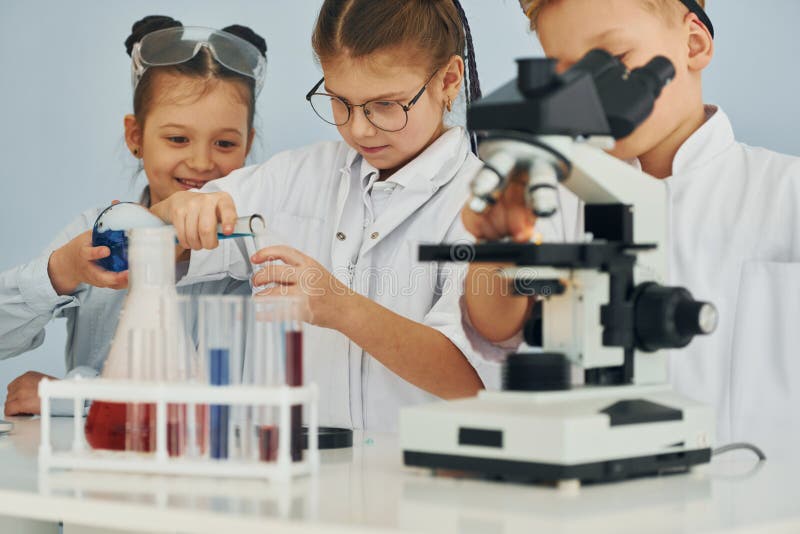 Using Microscope. Children in White Coats Plays a Scientists in Lab by ...
